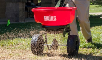 A seed spreader in use on a lawn